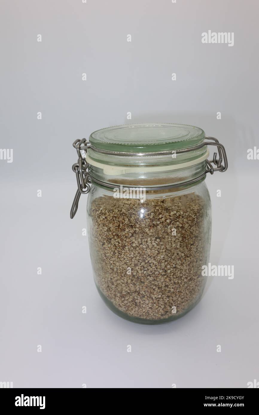 Glass jar filled with dried sesame seeds on a white background Stock ...