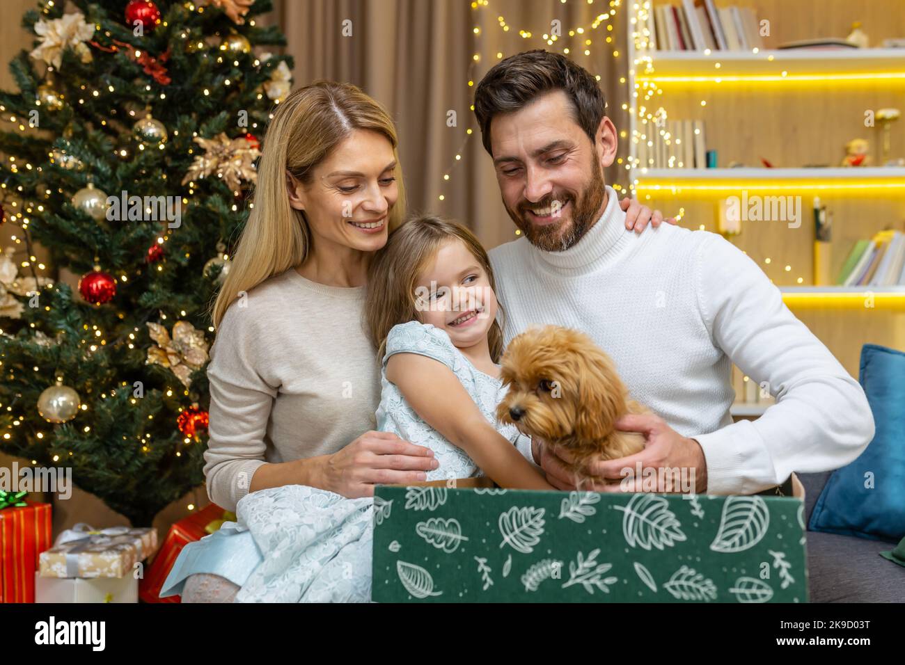Happy parents make a surprise gift of a small dog puppy from Santa to a ...