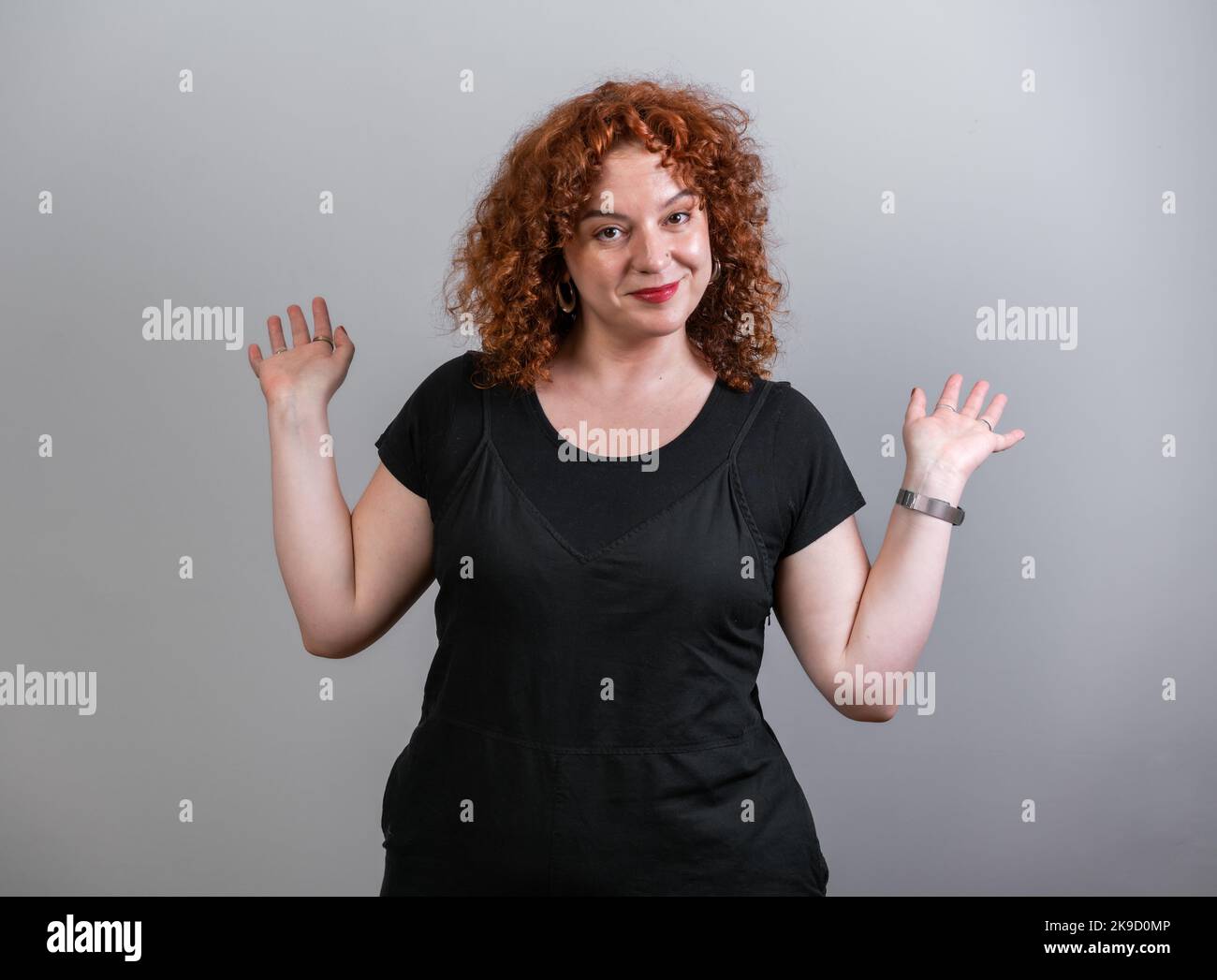Happy woman with red curly hair posing on grey background, with copy ...
