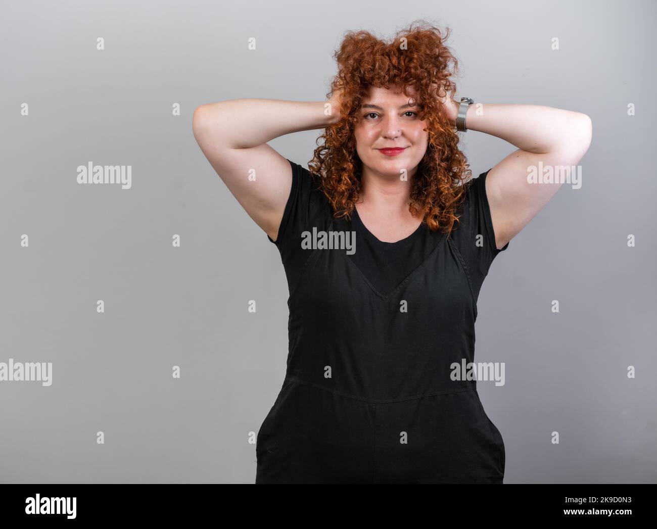 Happy woman with red curly hair posing on grey background, with copy ...
