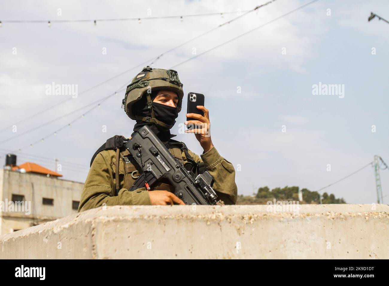 An Israeli soldier seen using his phone at an Israeli checkpoint in the ...