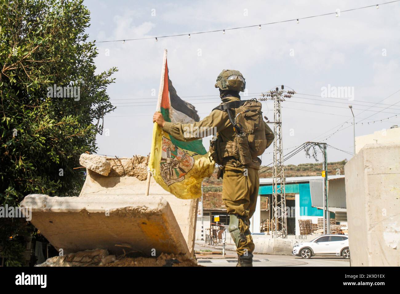An Israeli soldier removes the Palestinian flag placed on a military ...
