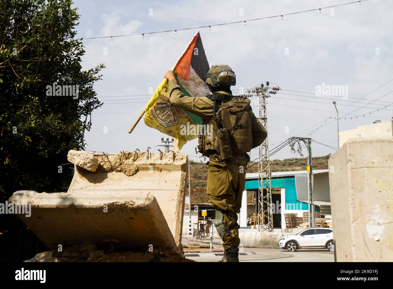 An Israeli soldier removes the Palestinian flag placed on a military ...