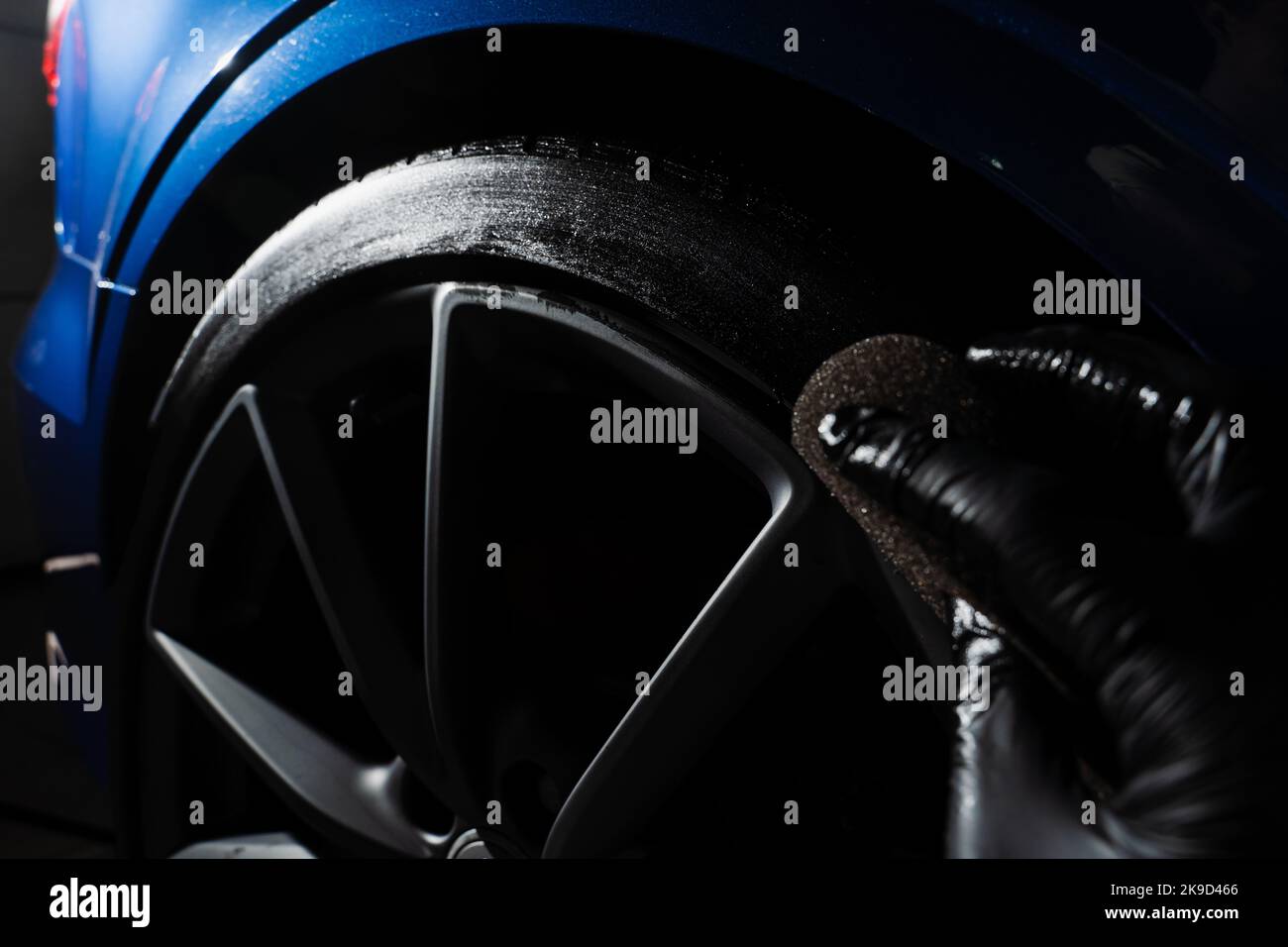 Tire blackening process. Auto detailing service worker applies rubber ...