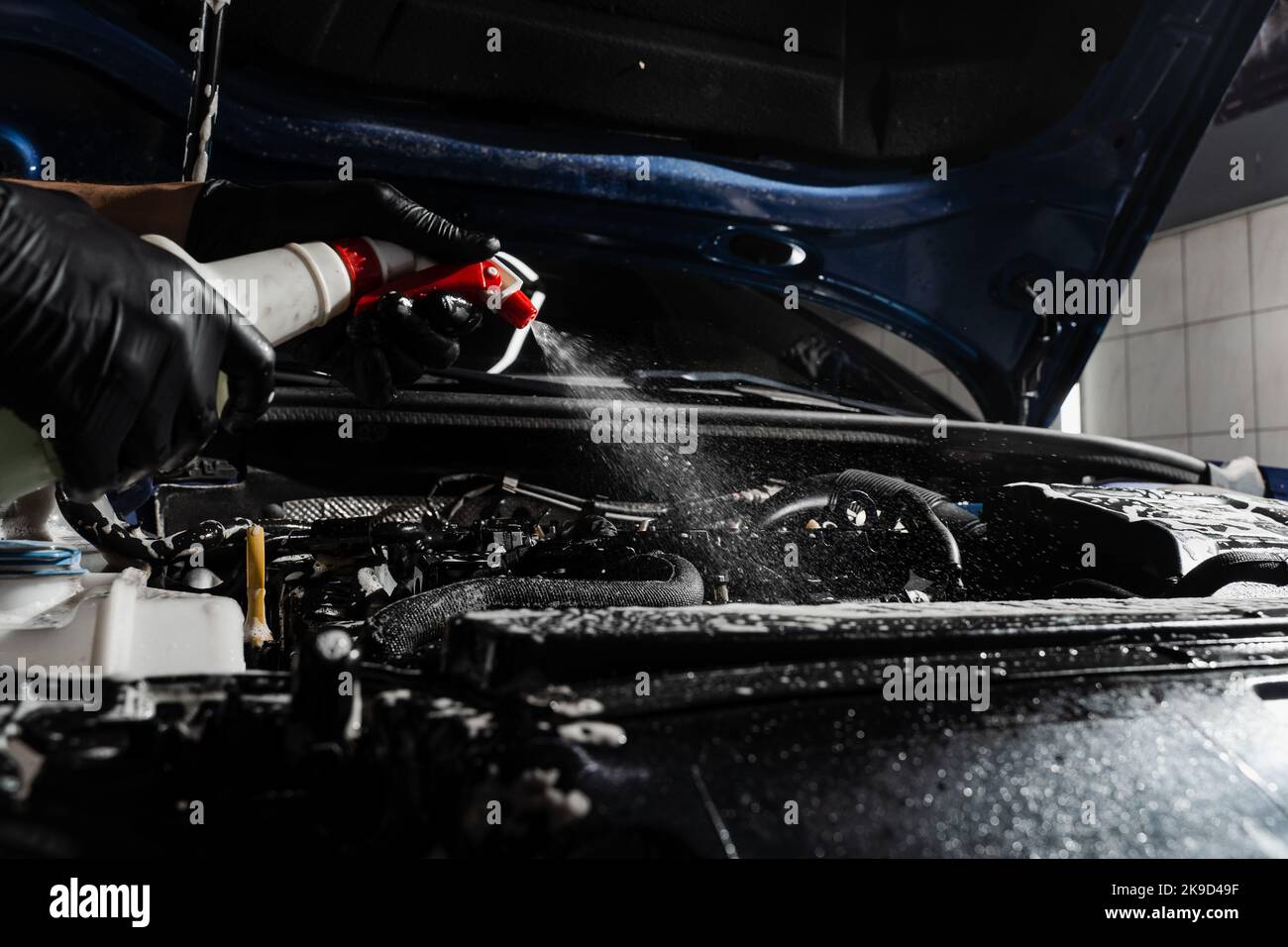 Washing car engine with spray and detergent in detailing auto service ...
