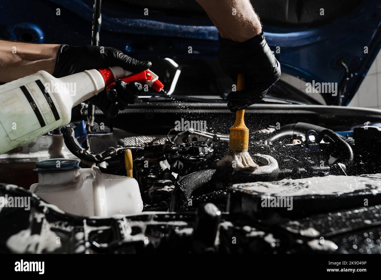 Washing car engine with spray, brush and detergent in detailing auto ...