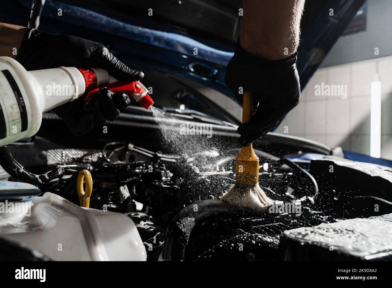 Washing car engine with spray, brush and detergent in detailing auto ...