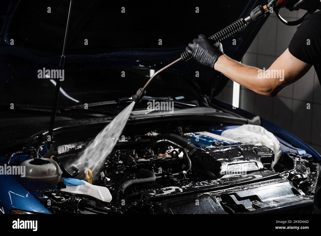 Pouring water on car engine. Washing car engine with spray, brush and ...