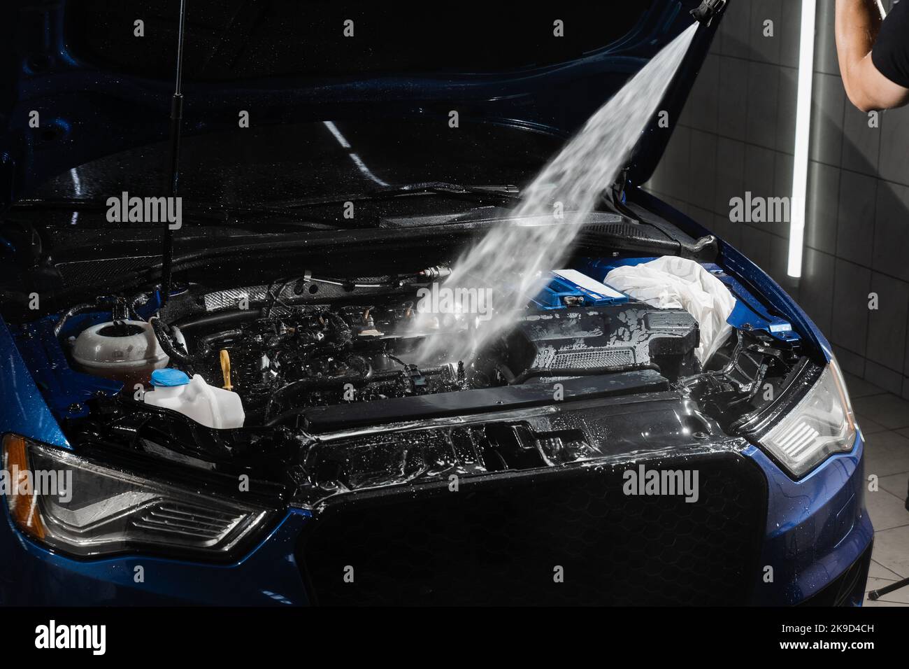 Pouring water on car engine. Washing car engine with spray, brush and ...