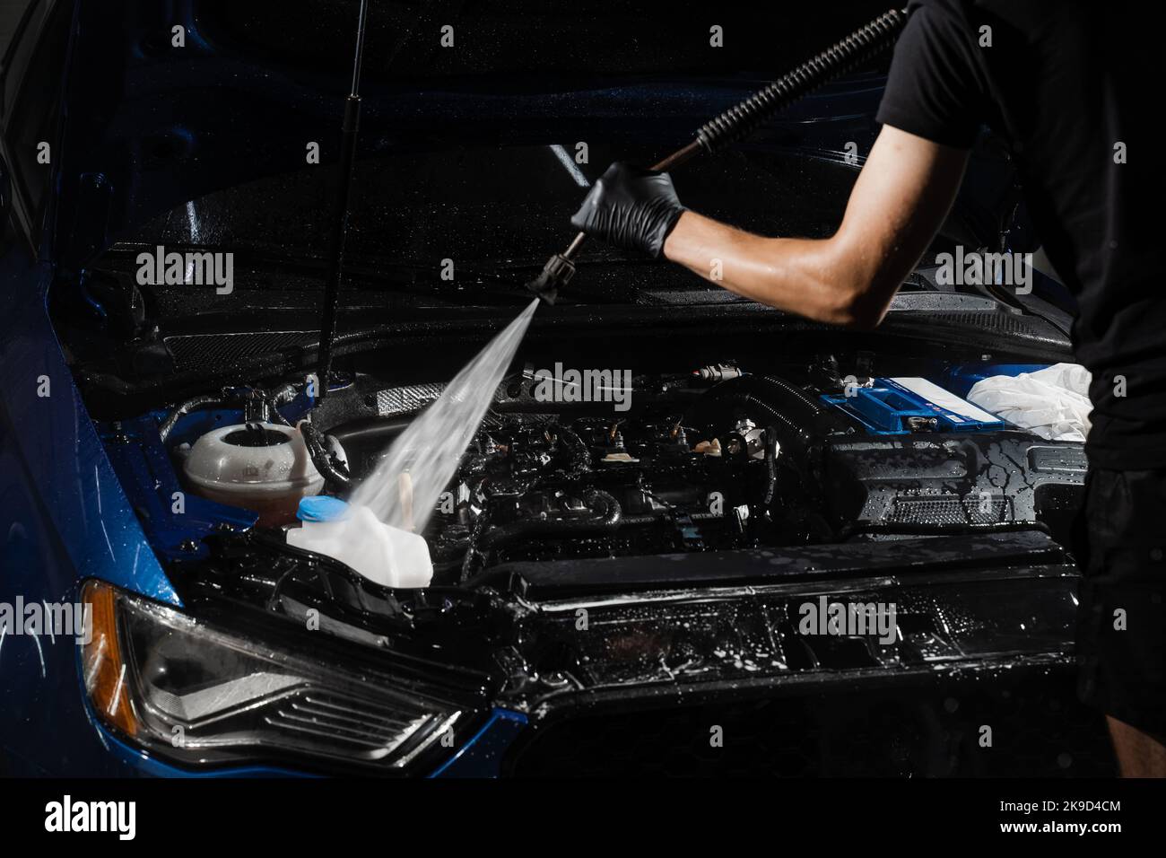 Pouring water on car engine. Washing car engine with spray, brush and ...