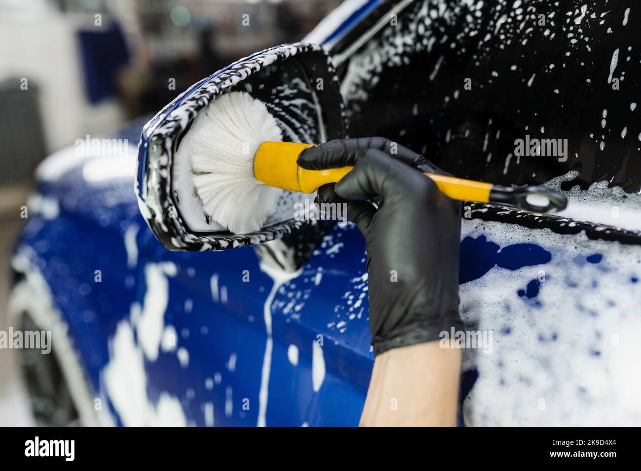 Hand brush washing of car side mirror with foam in car detailing ...