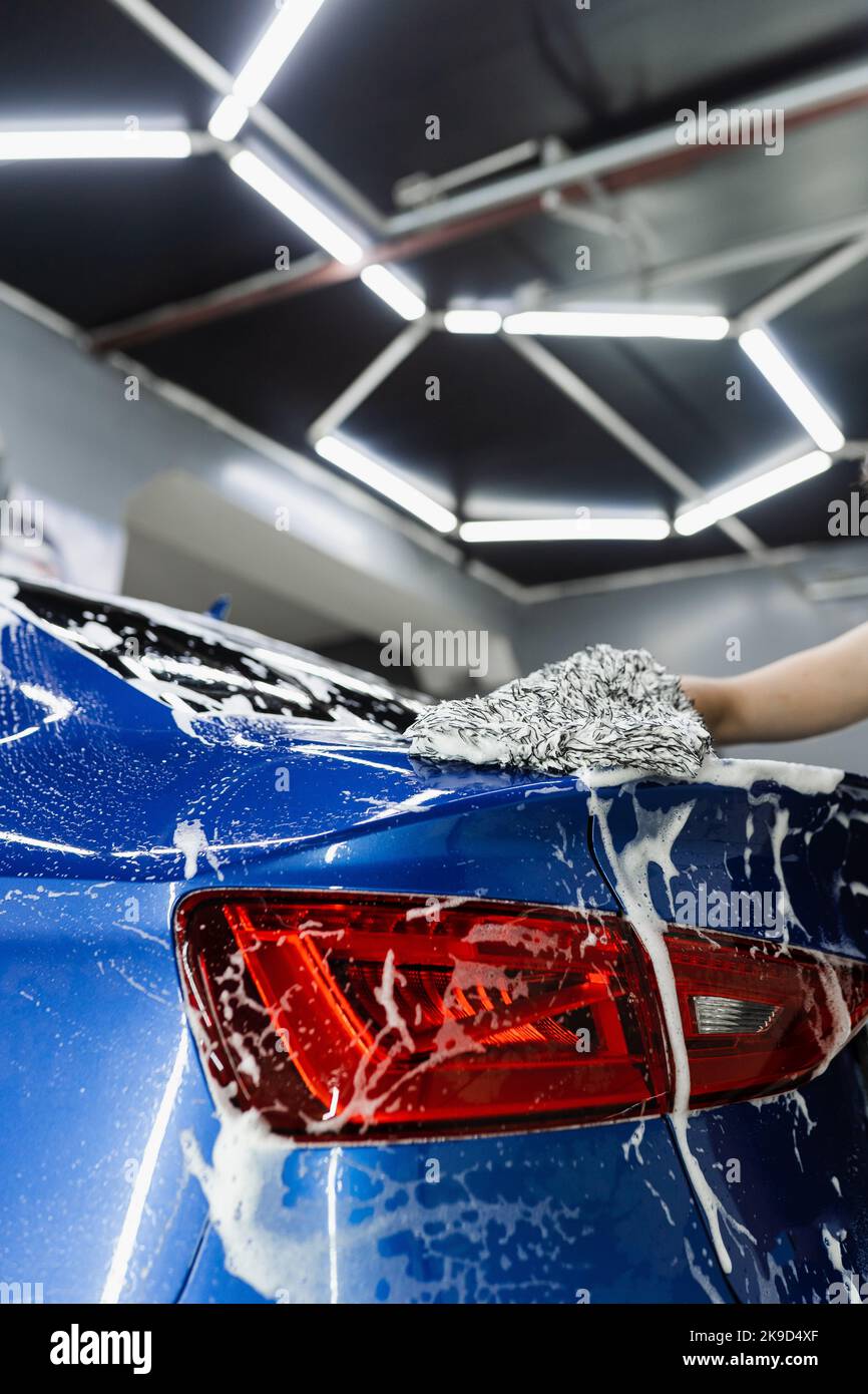 Hand washing with microfiber glove with foam car body in garage. Car ...