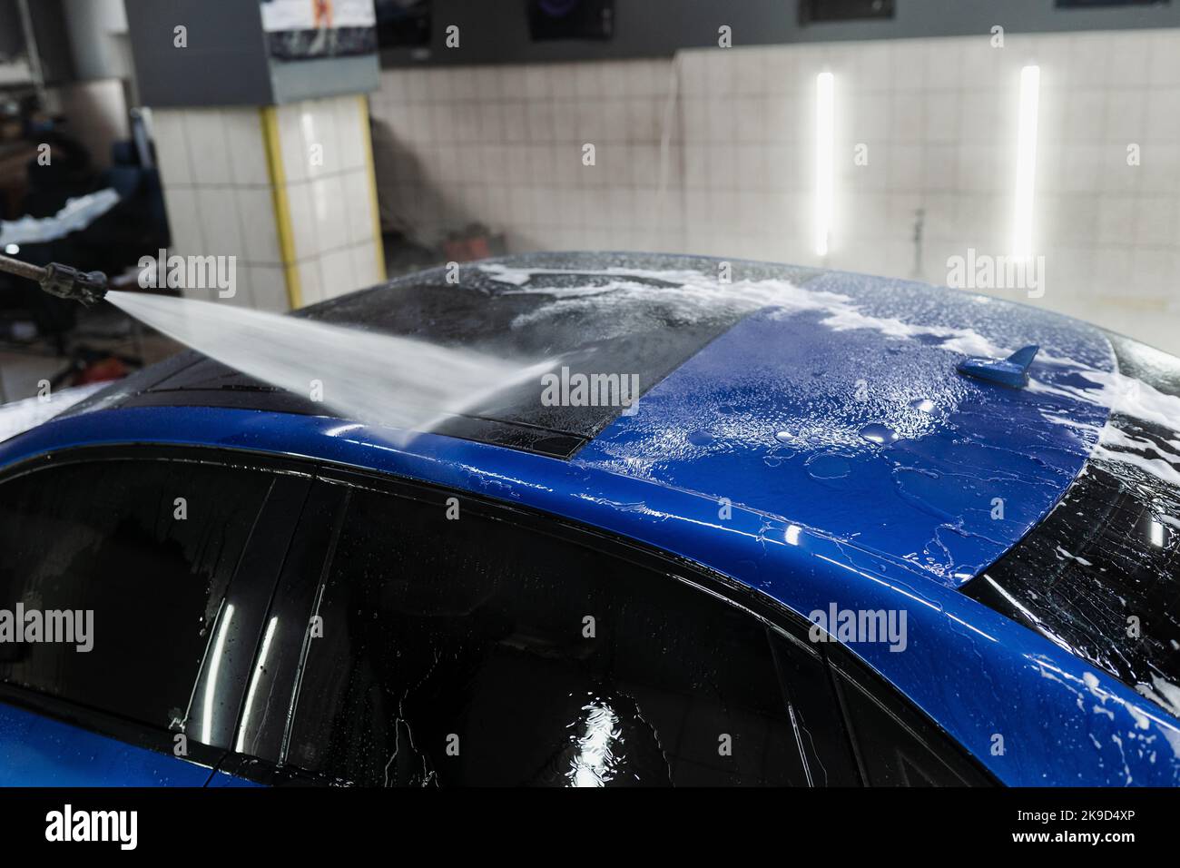Spraying water on car to wash off foam in the garage. Process of ...