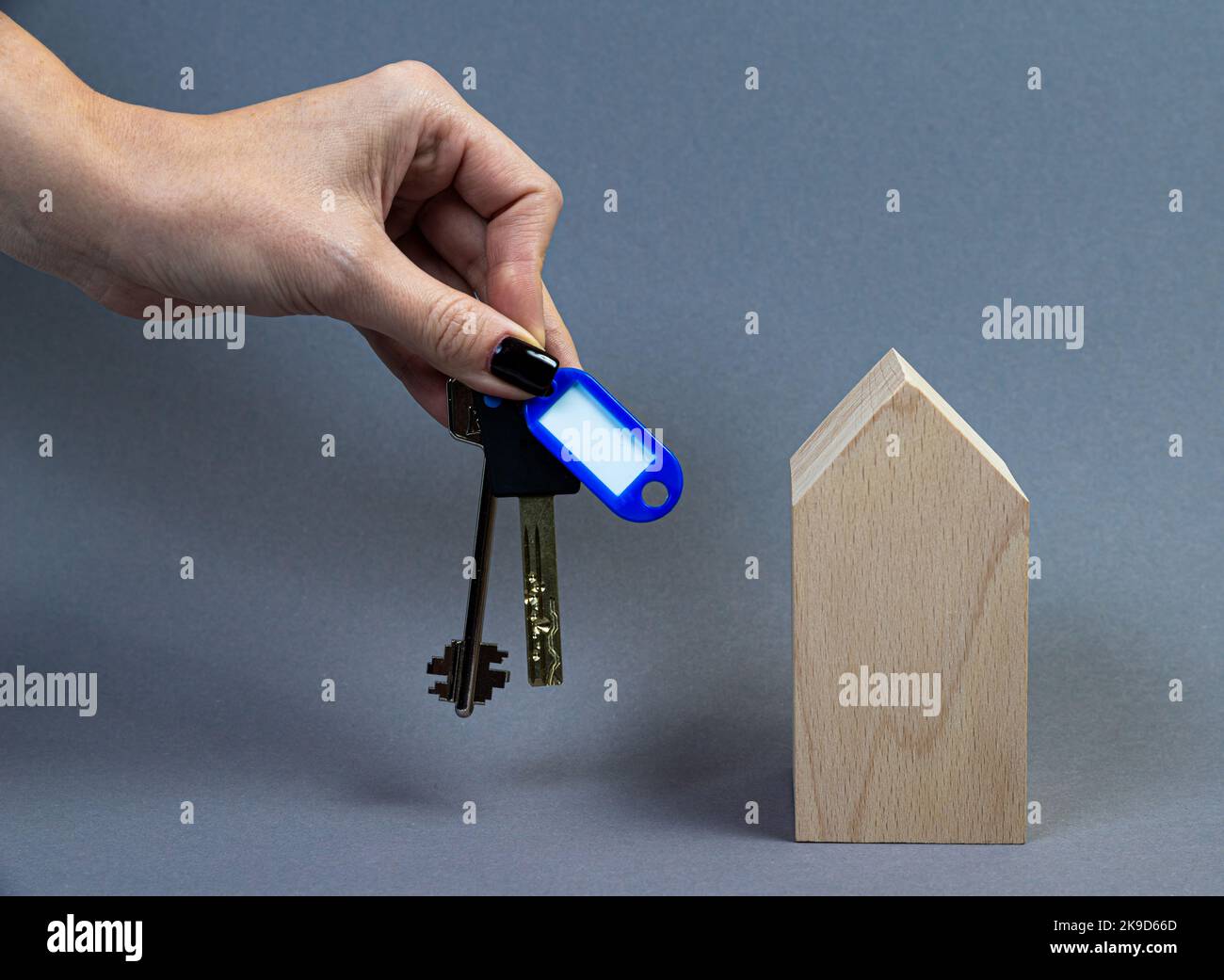 Houses symbol Hand with metal key on on grey background. Real estate ...