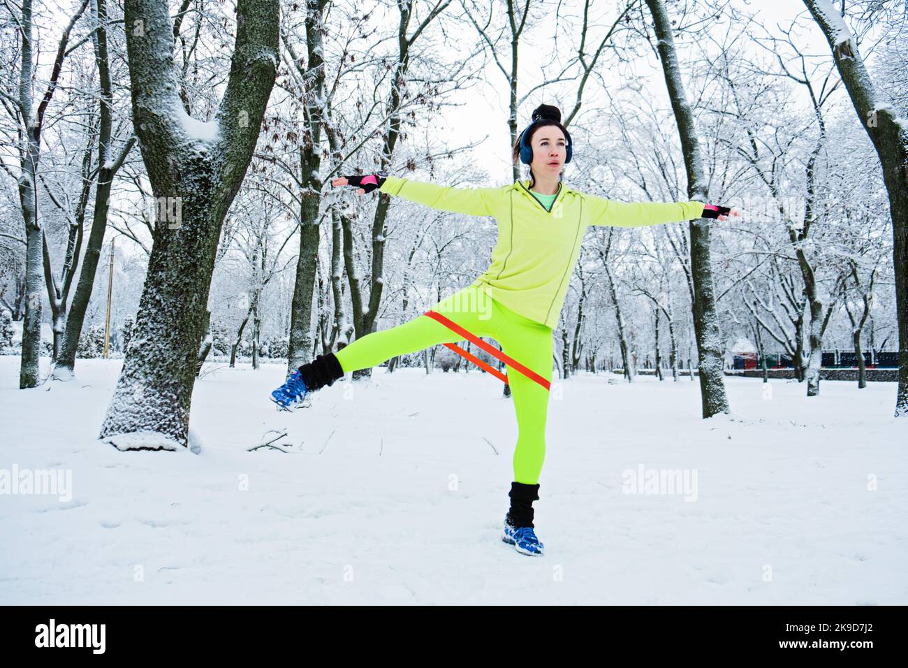 Athletic fitness woman doing exercise with resistance band on winter ...