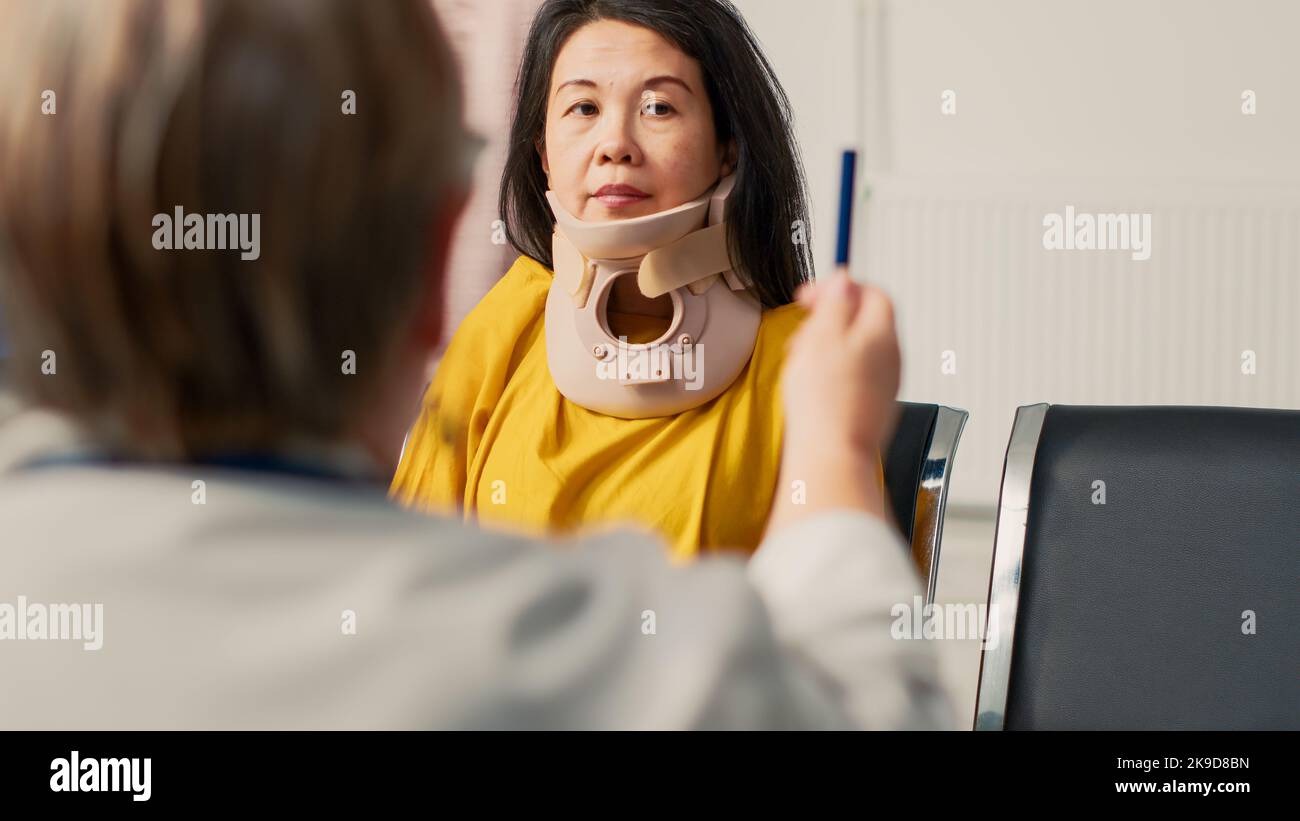 Physician consulting asian patient with cervical neck collar, checking ...
