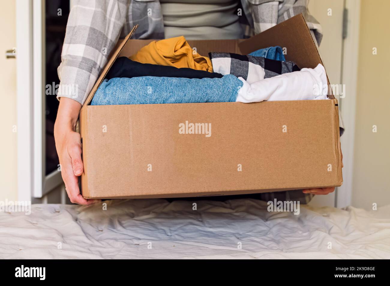 Woman's hands holding a box full of clothes. Home organization and ...