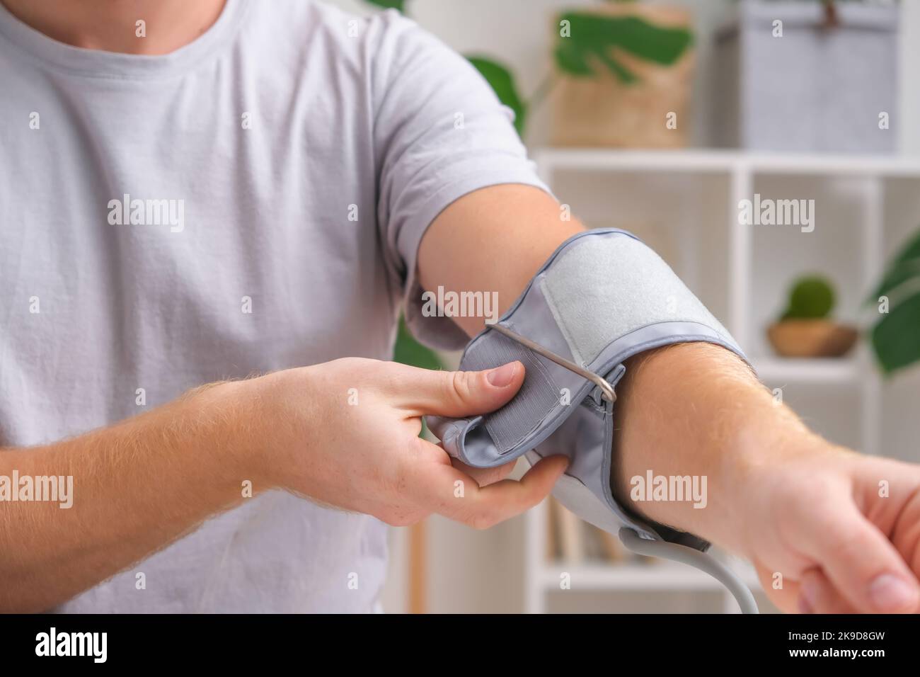 A man measures blood pressure with a white electric tonometer lying on ...