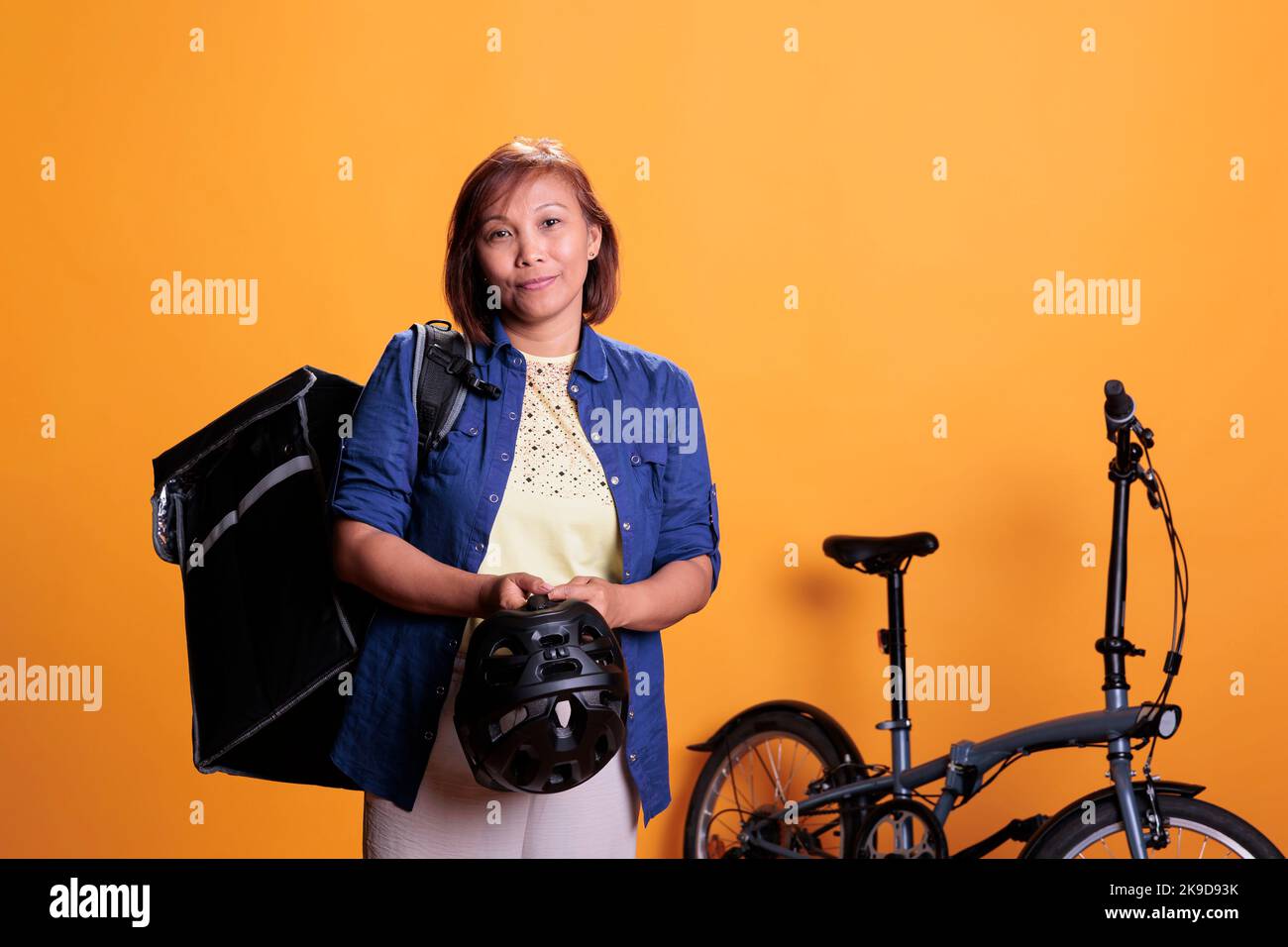 Elderly deliverywoman carrying thermal delivery backpack standing ...