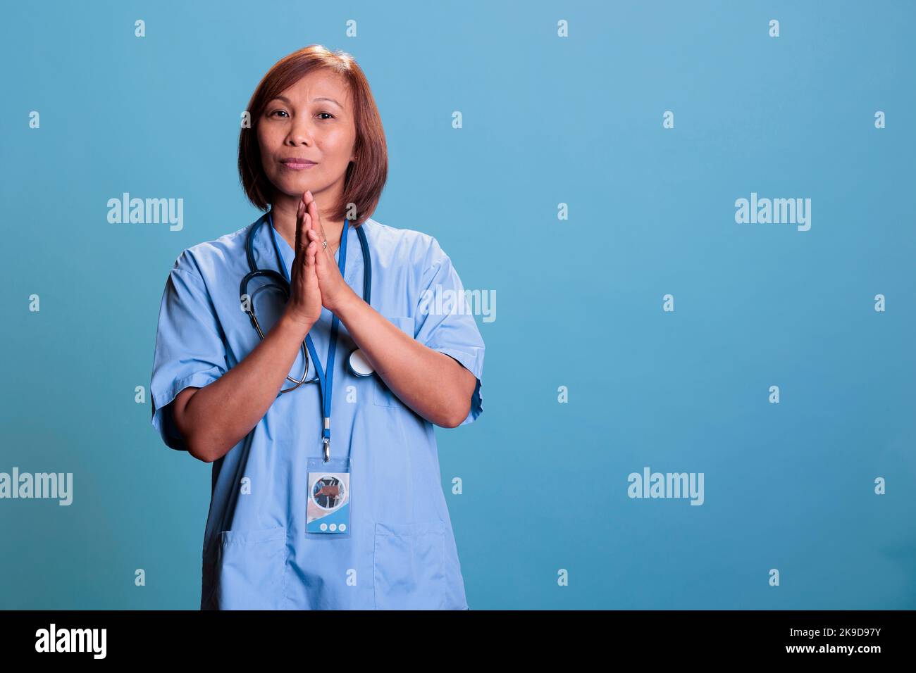 Religious medical assistant holding hands praying to god during patient ...