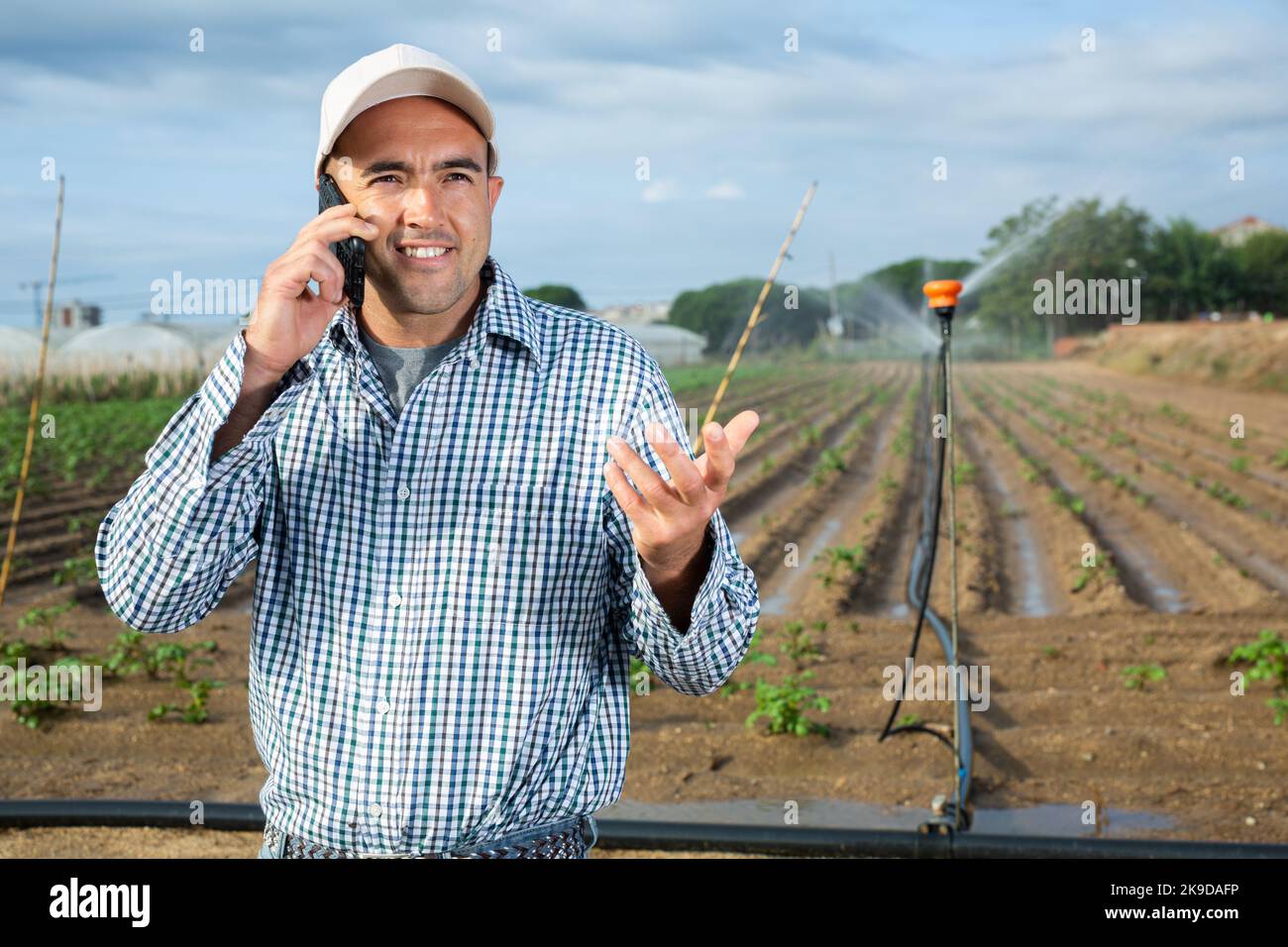 Owner of farm is talking on mobile phone against background of ...
