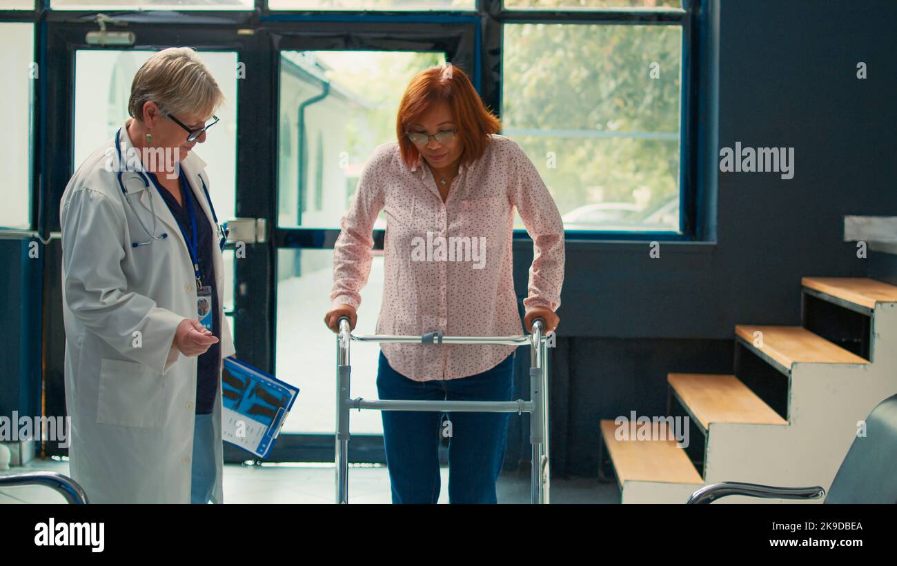 Elderly medic giving support to injured patient trying to walk around ...