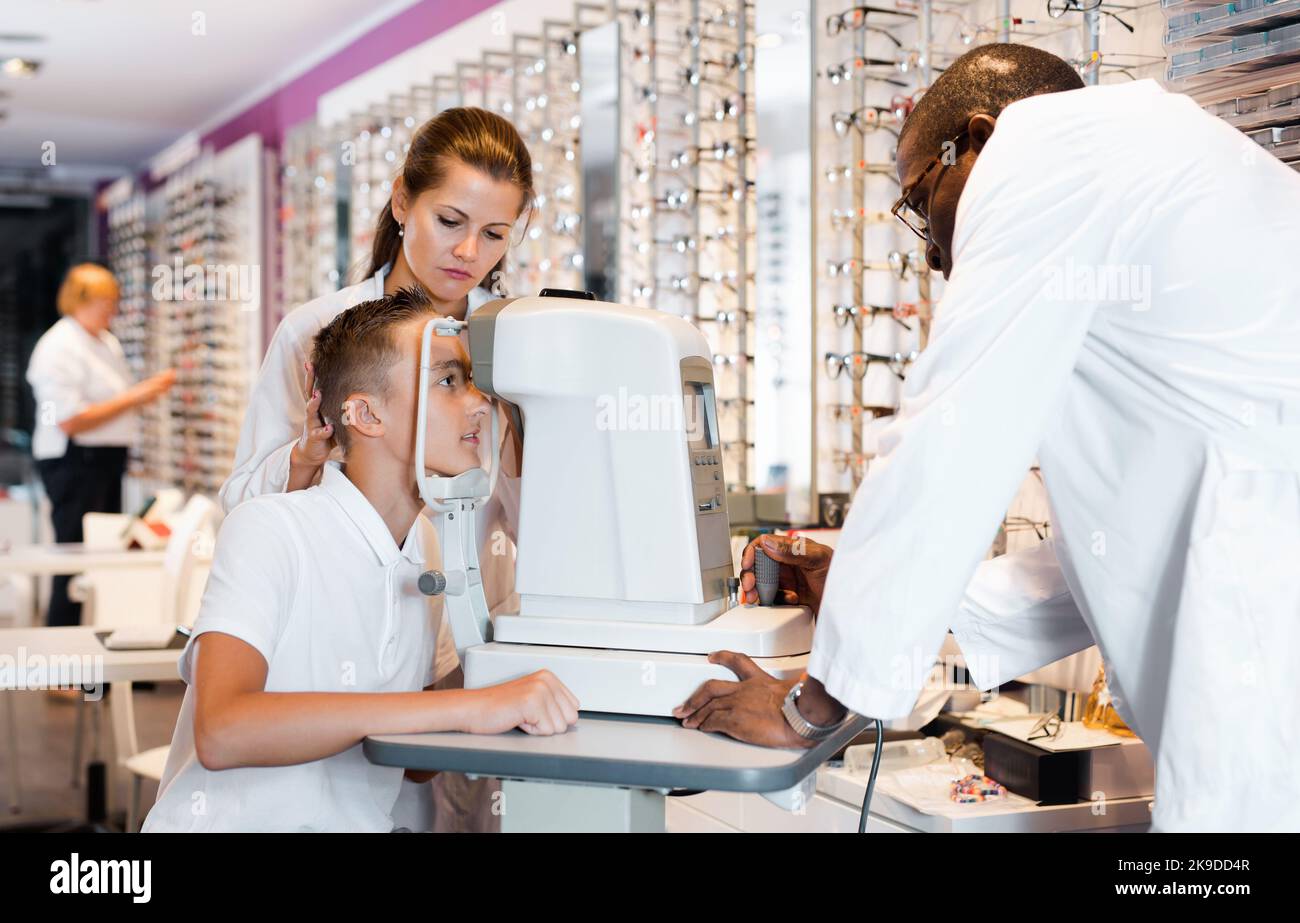 Two qualified optometrists using refractometer for testing eyesight of ...