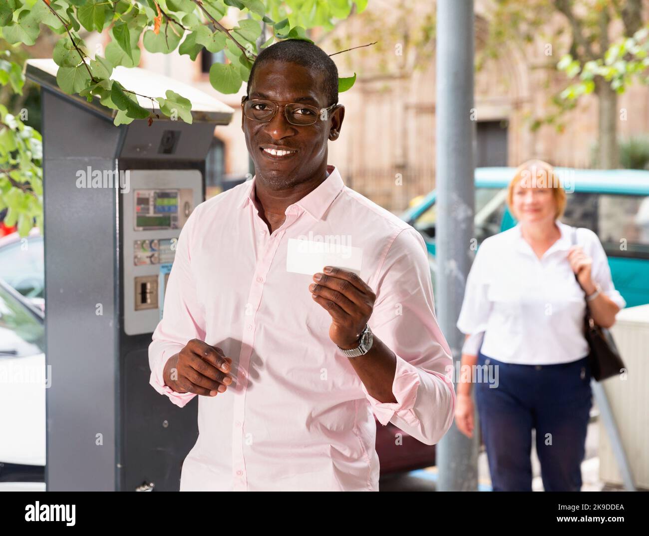 Cheerful African American man showing ticket for car parking purchased ...