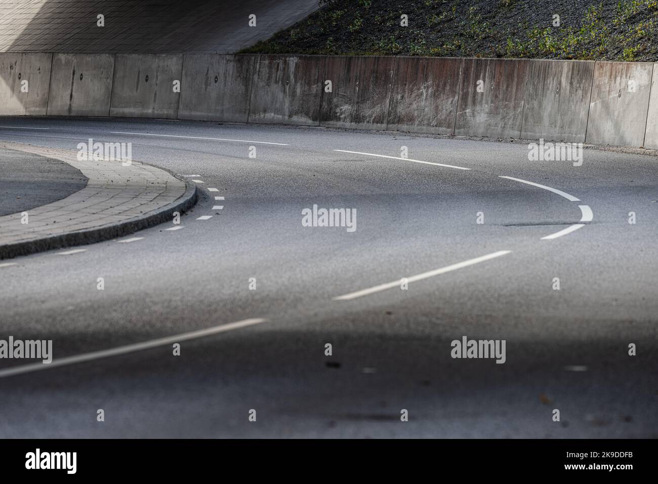 Left turning road underneath bridges Stock Photo - Alamy
