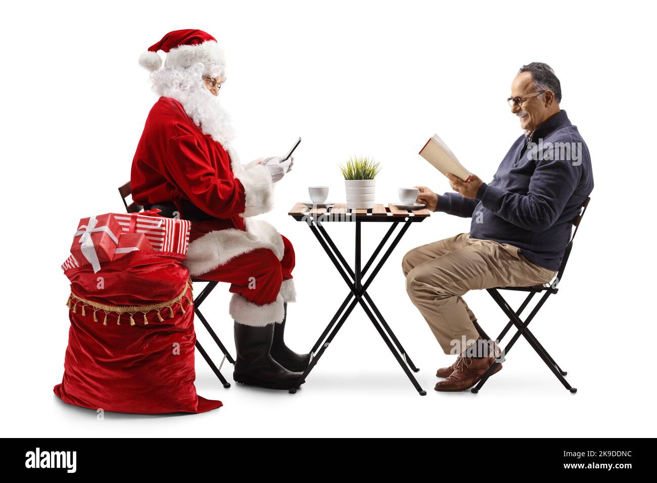 Santa Claus Using Smartphone And A Mature Man Sitting At A Table And