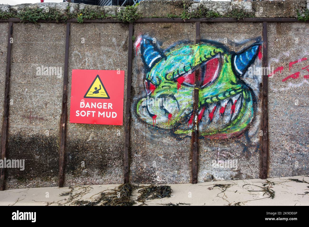 Graffiti of a demonic animal head next to a Danger Soft Mud warning ...
