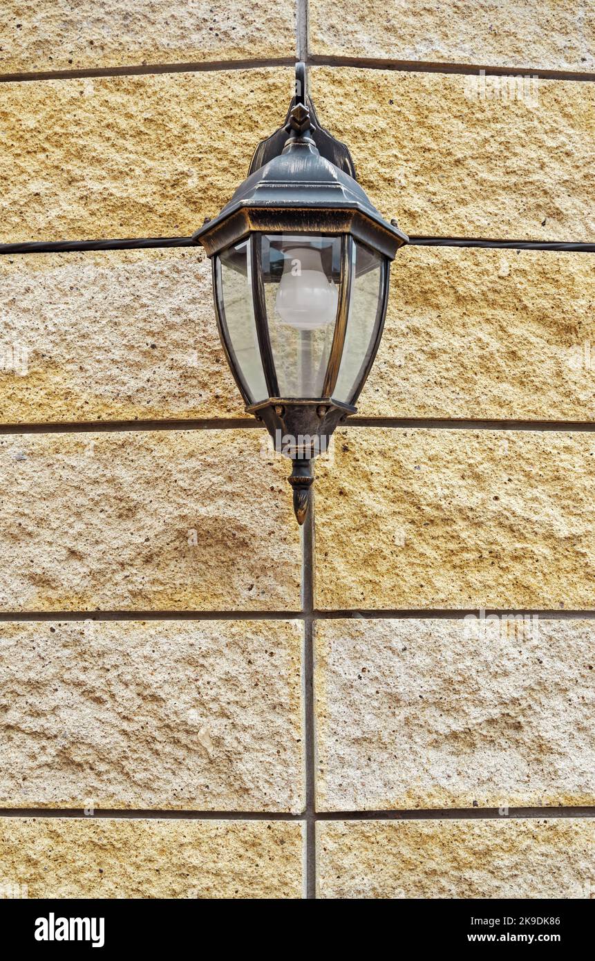Wall mounted street lamp mounted on stone fence on made volcanic tuff ...