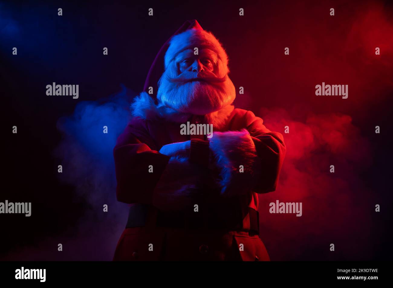 Santa Claus stands with his arms crossed on his chest in blue red neon ...