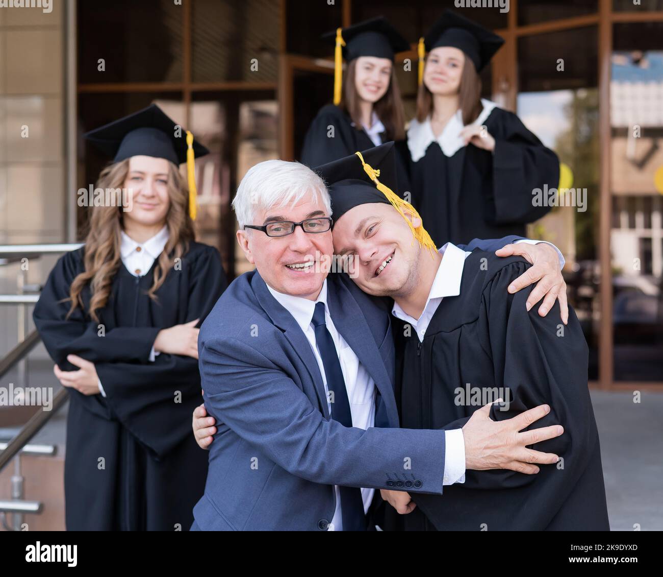 Father and son embrace at graduation. Parent congratulates university ...