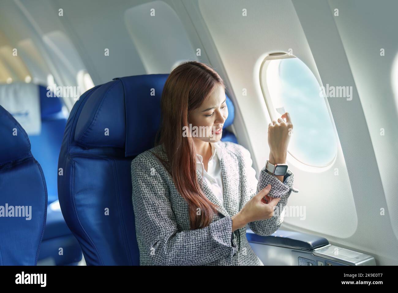 Portrait of a young Asian businesswoman smiling while riding a plane ...