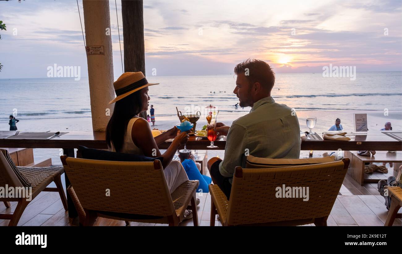 Dinner during sunset with fish and Thai food, a couple of men and women ...