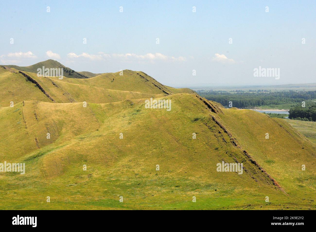 A chain of high hills with rock formations on top, on a sunny summer ...