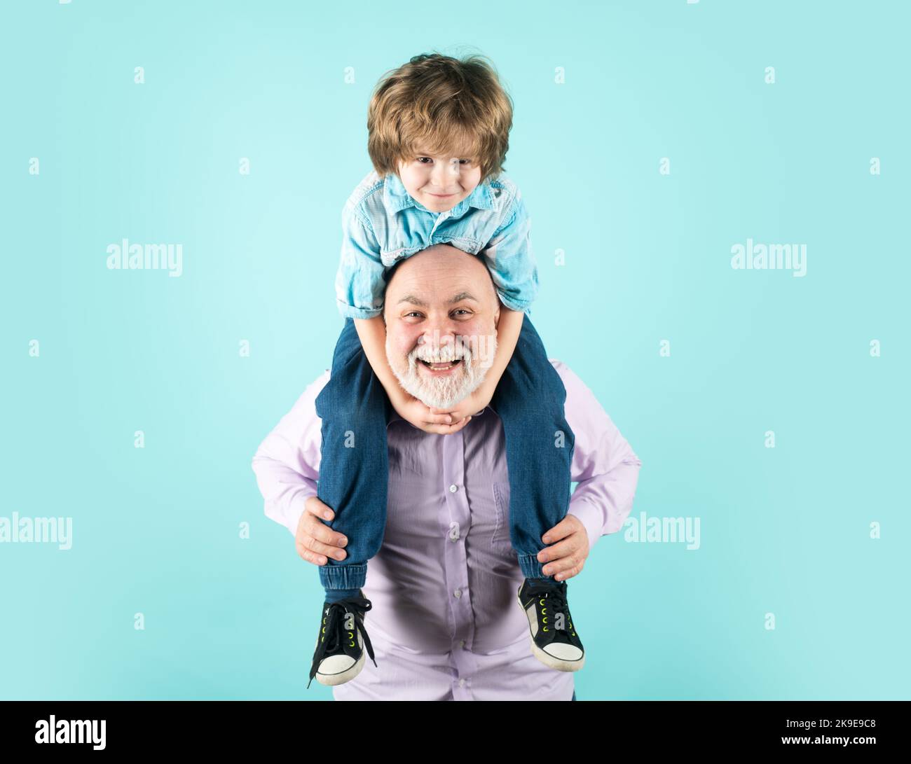 Grandfather and son piggyback ride with funny face isolated on blue in ...