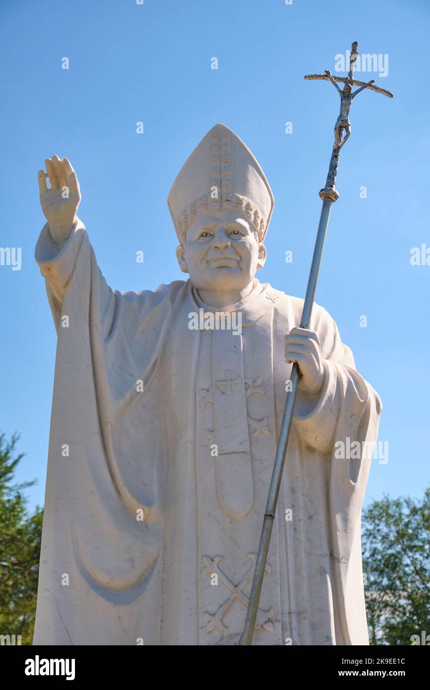 A white stone, marble carved statue of Pope John Paul II, in front of ...