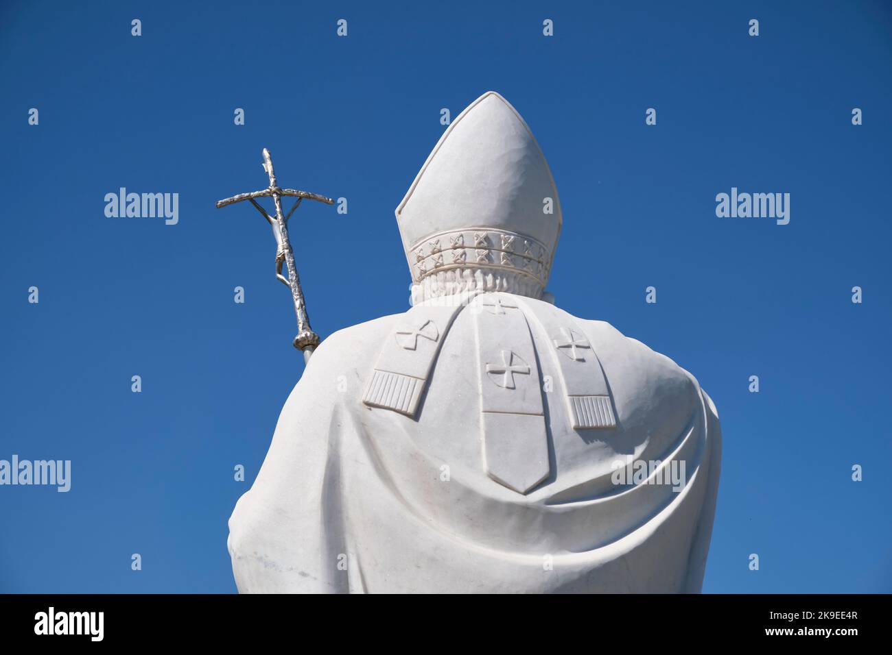 A white stone, marble carved statue of the back of Pope John Paul II ...