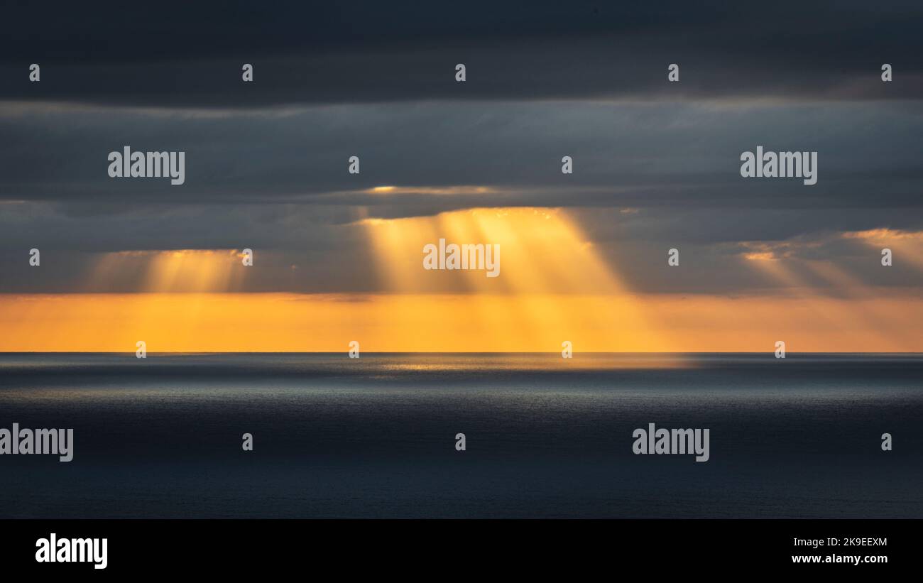 Crepuscular light rays shining through clouds over the ocean Stock ...