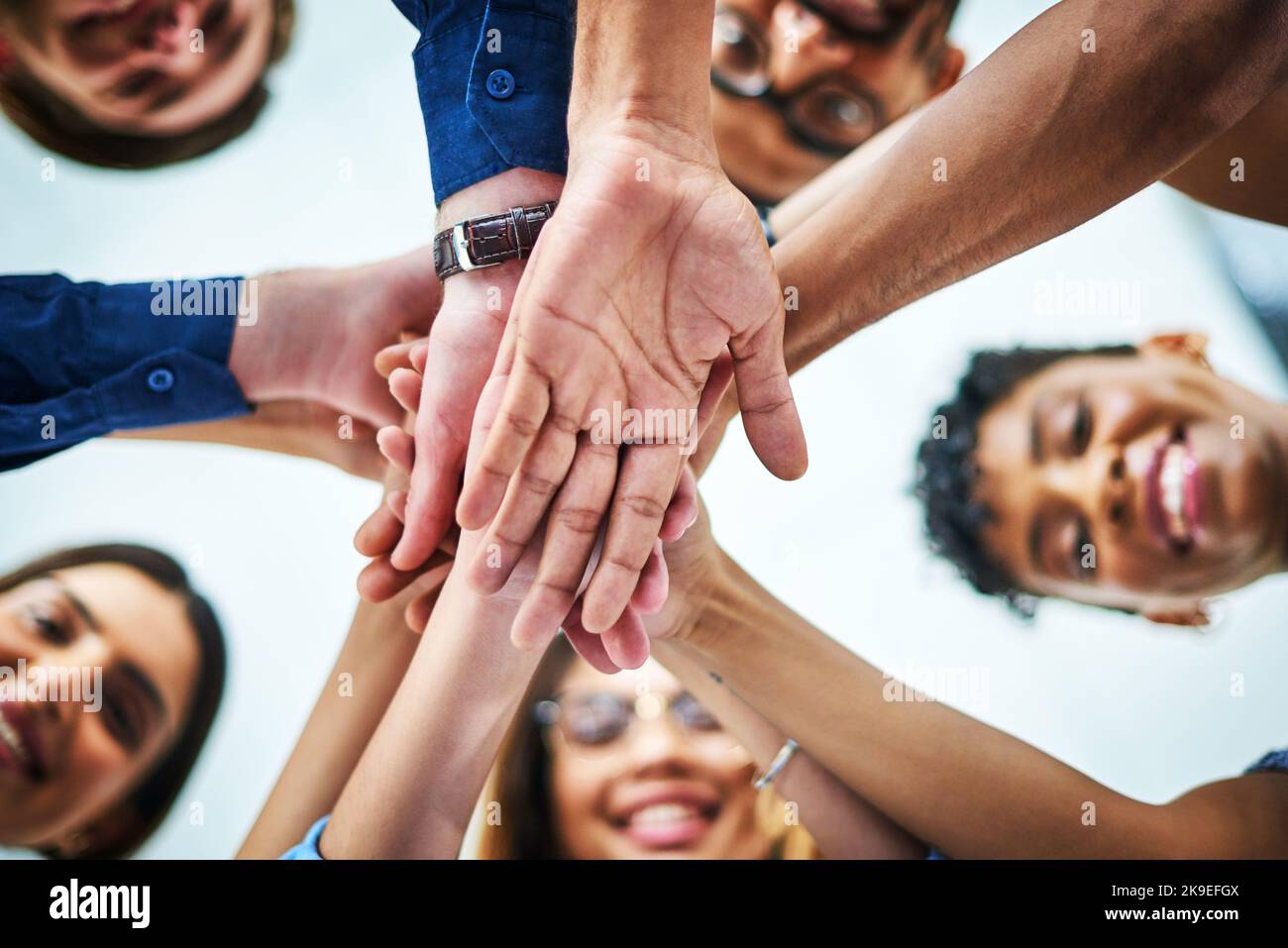 Were so ready for this. Low angle shot of a group of unrecognizable businesspeople joining their ...