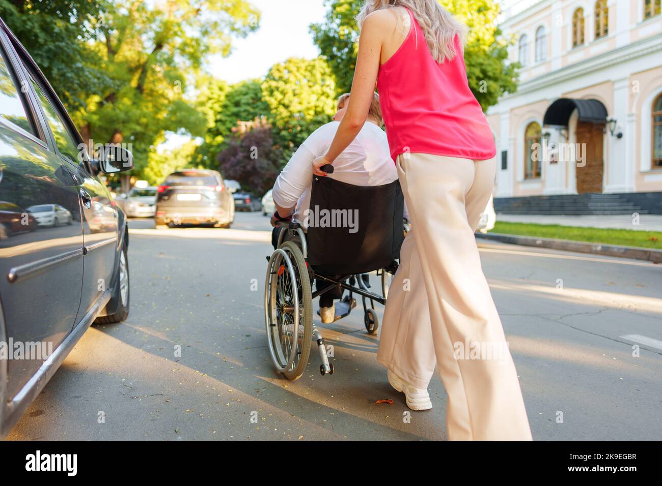 Young female caregiver pushing wheelchair with female person with ...