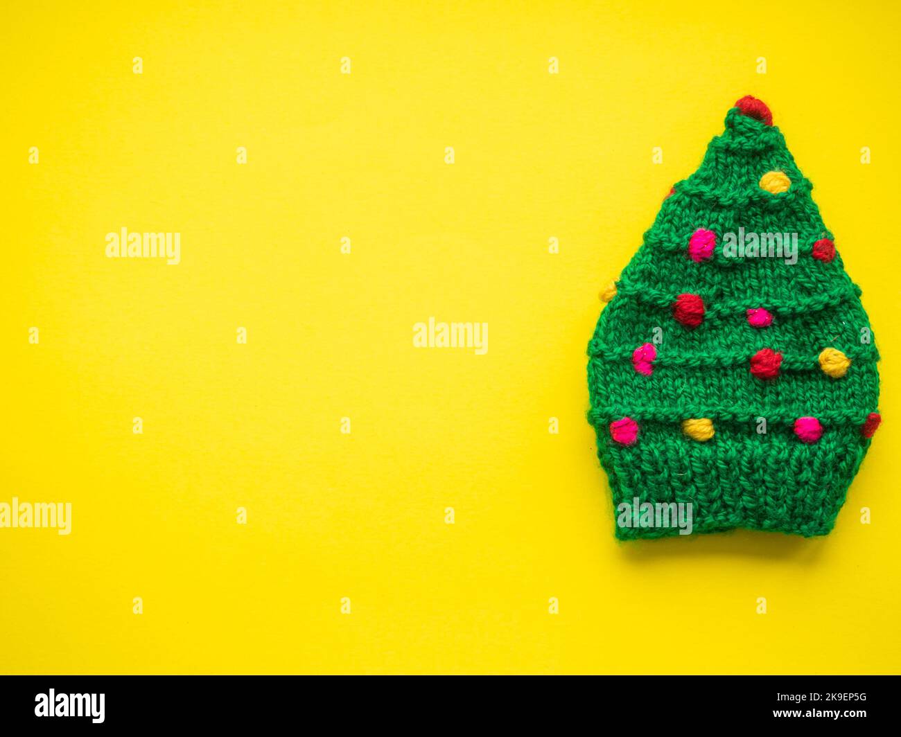 Green knitted hat in the form of a Christmas tree on a yellow ...