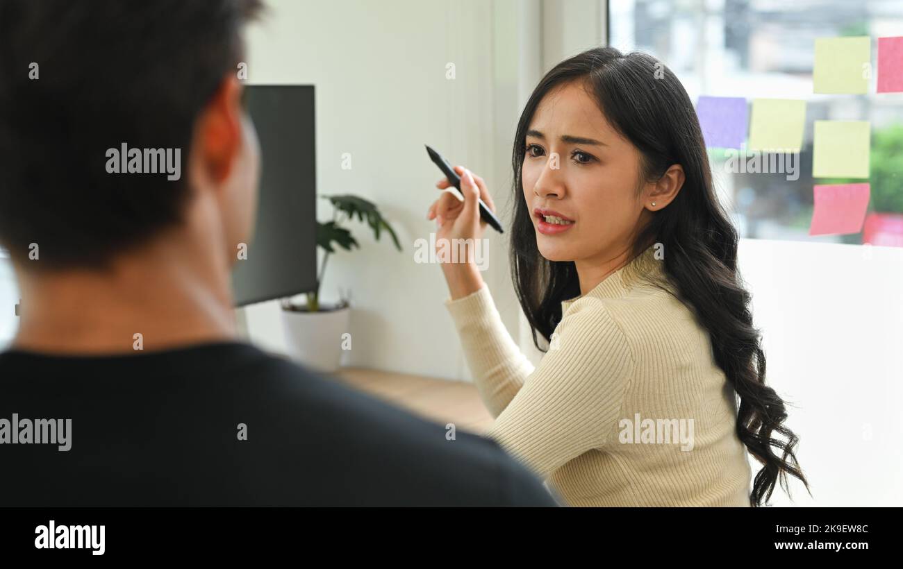 Serious young woman explaining task or discussing business strategy ...