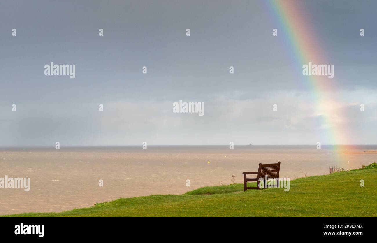 Rainbow over the ocean and wooden bench on the coast for relaxing ...