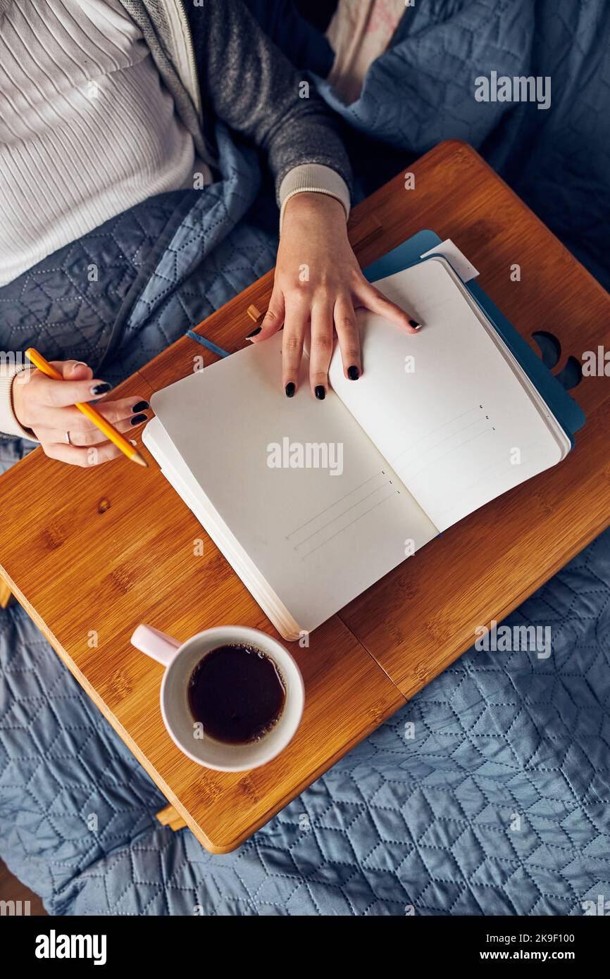 Student learning at home. Young woman making notes, reading and ...