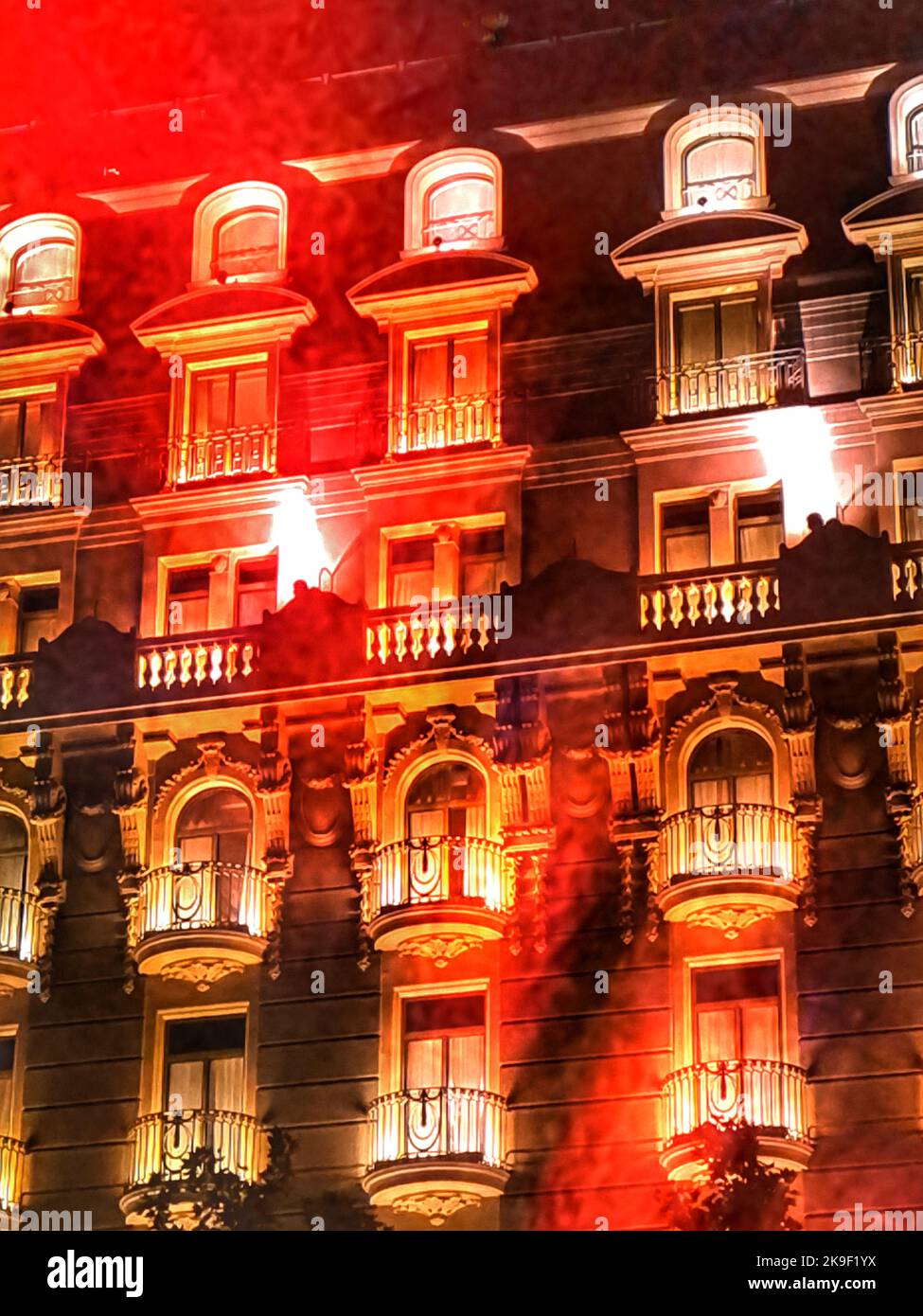 Classic style apartment building at night with flashes of red light to ...