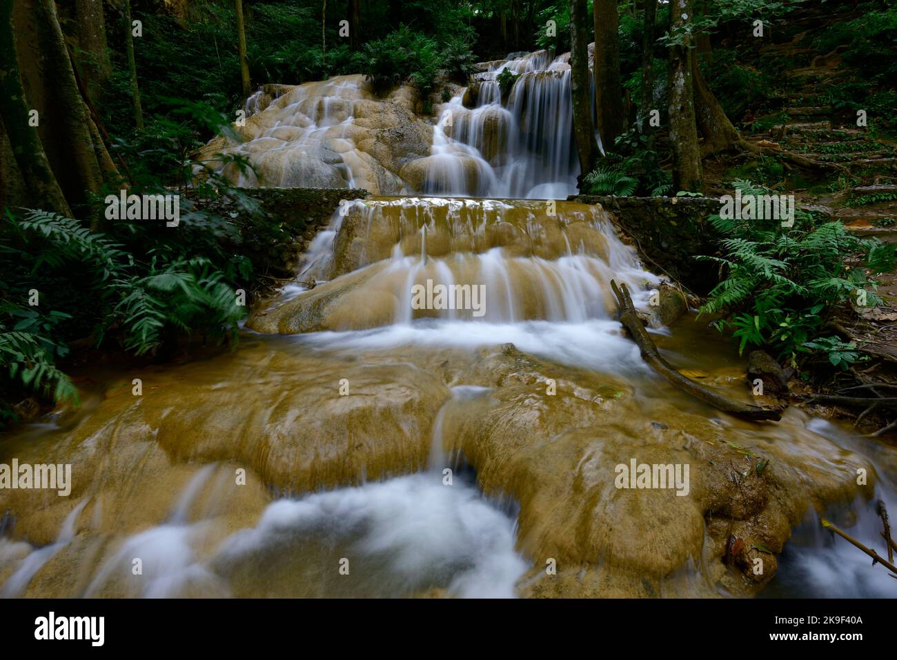 A beautiful Waterfall in the green forest with green water flowing on ...