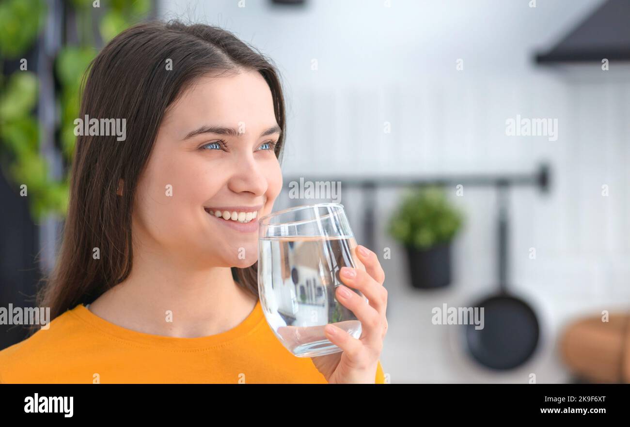 Healthy lifestyle. Female drinking still water standing. Young smiling ...